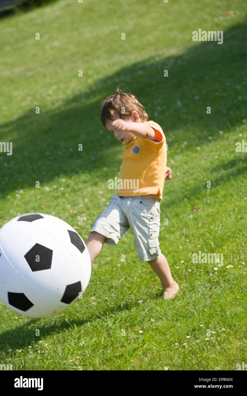 Young boy playing with ball in the grass Stock Photo - Alamy