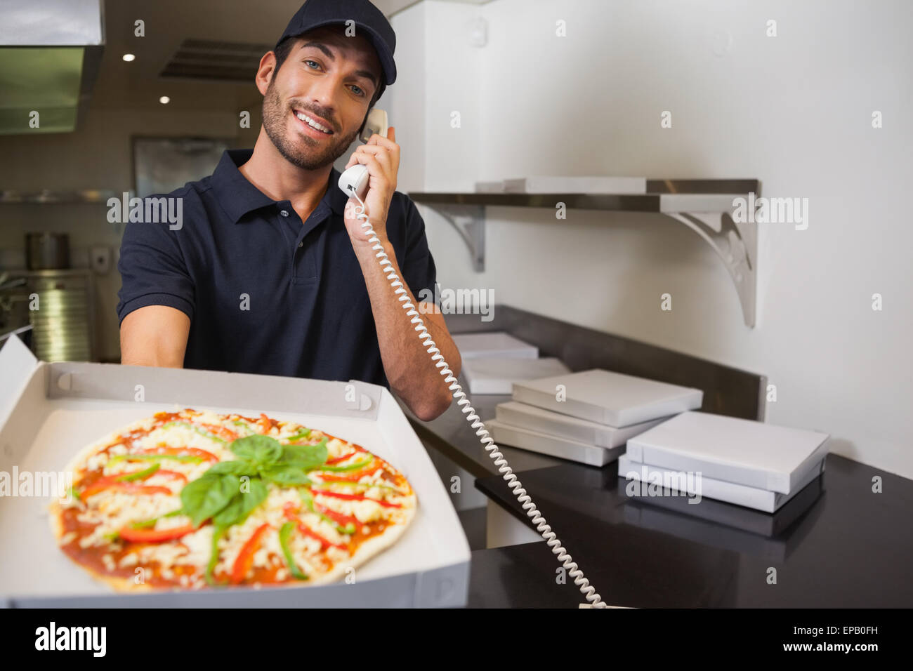 Smiling pizza delivery man taking an order over the phone showing a ...