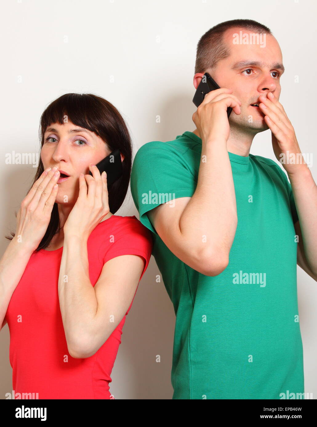 Shocked woman and man receive an unexpected message while talking on ...