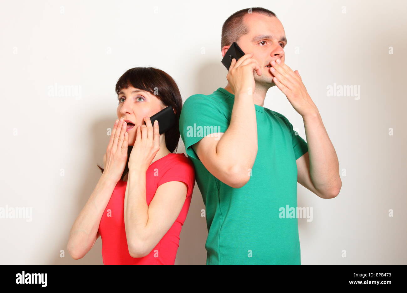 Shocked woman and man receive an unexpected message while talking on ...