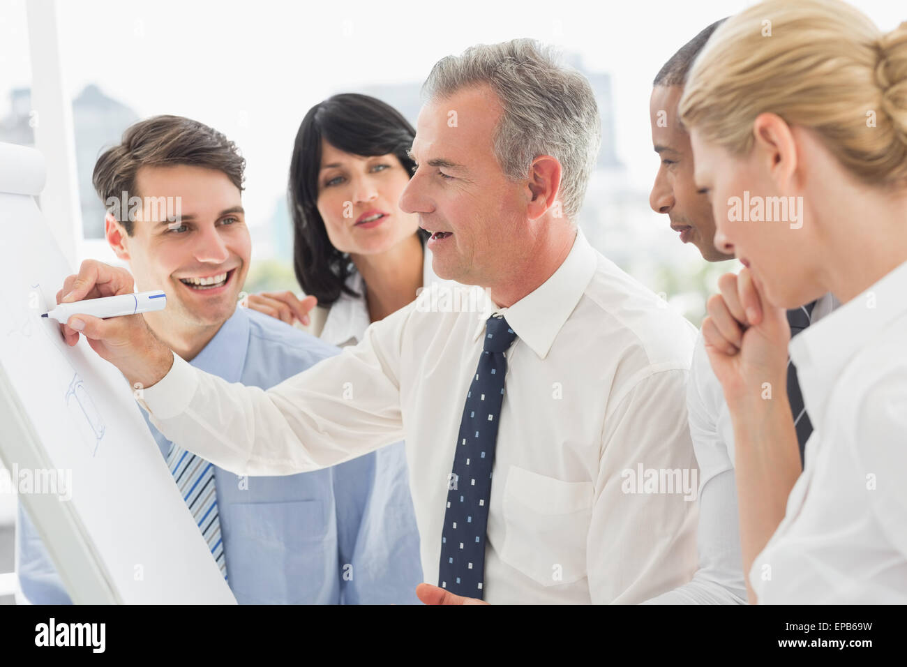 Smiling colleagues watching businessman writing on whiteboard Stock ...
