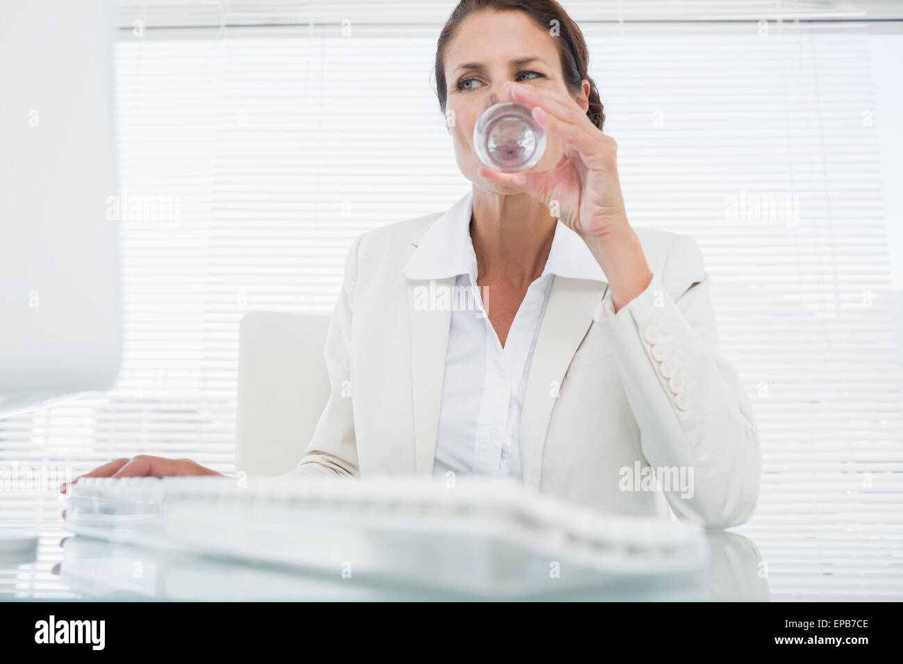 Businesswoman using computer while drinking water Stock Photo - Alamy