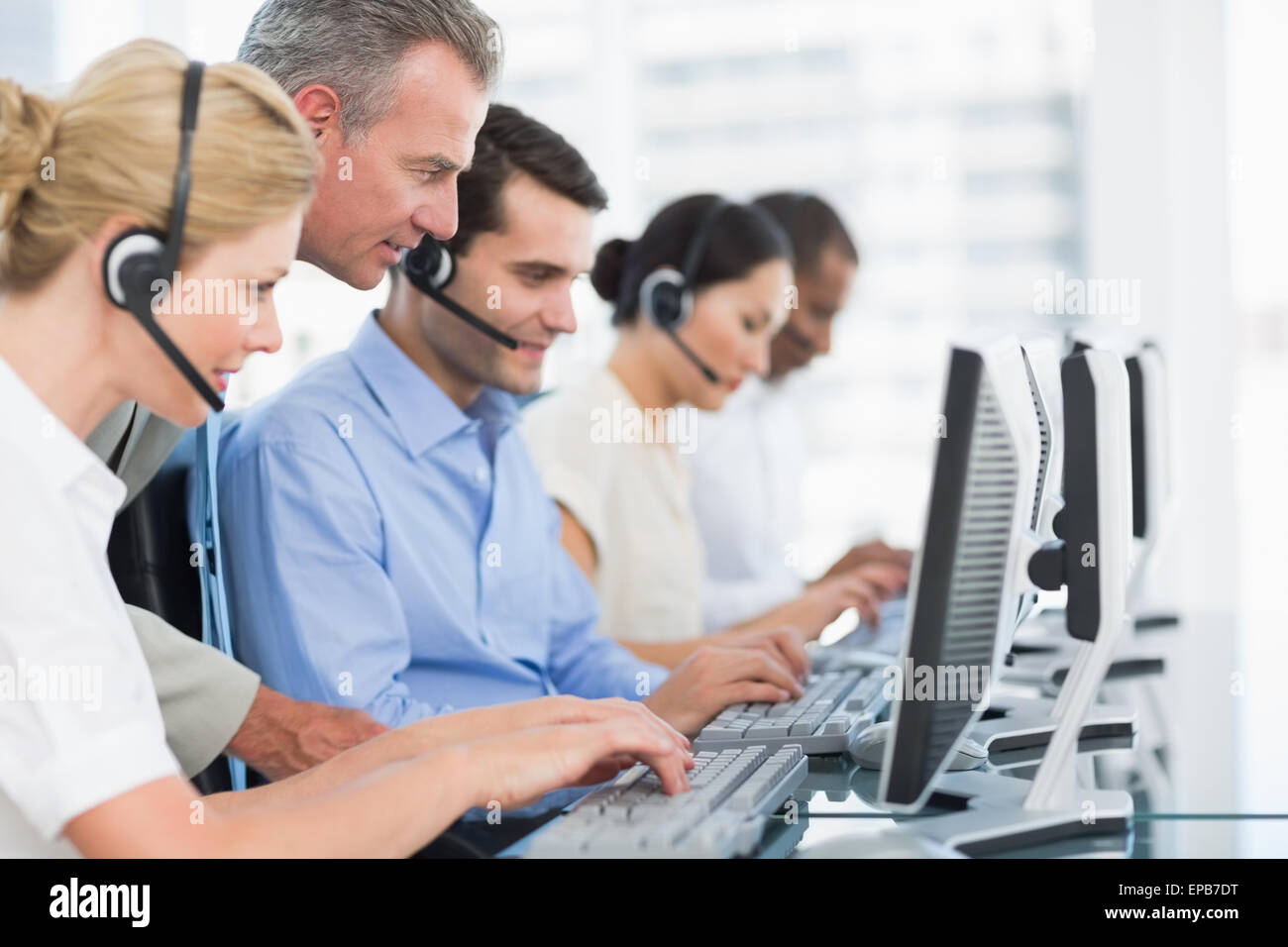 Manager and executives with headsets using computers Stock Photo - Alamy