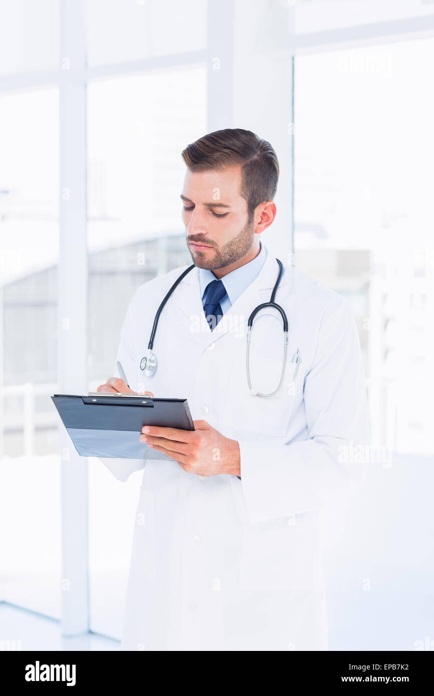 Concentrated male doctor writing reports in clipboard Stock Photo - Alamy