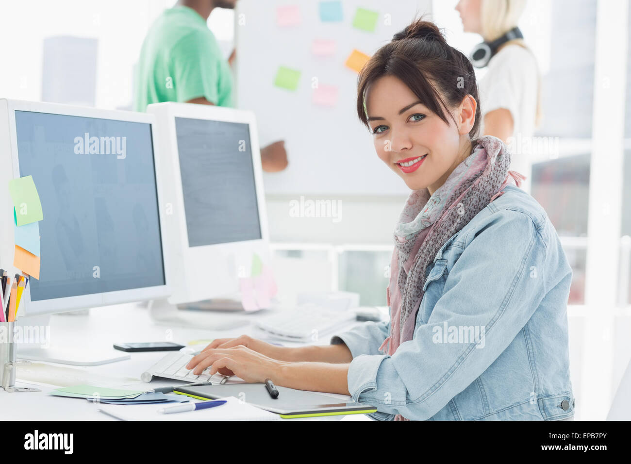 Portrait of an artist using computer with colleagues behind Stock Photo ...