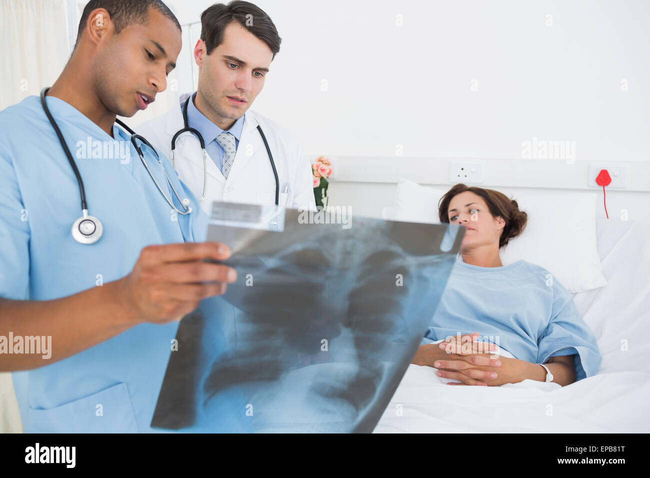 Doctors examining x-ray by patient in hospital Stock Photo - Alamy
