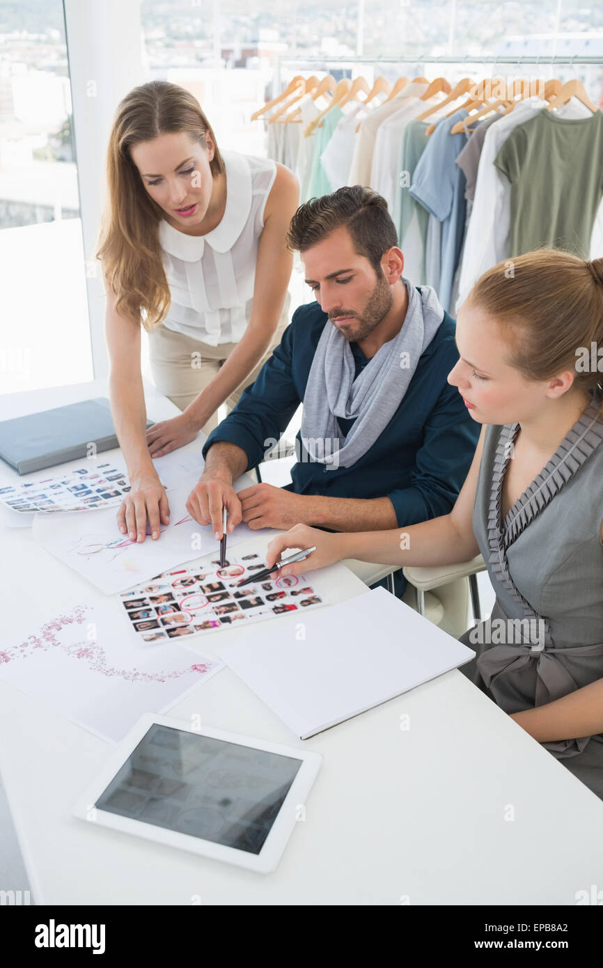 Three fashion designers discussing designs in a studio Stock Photo - Alamy