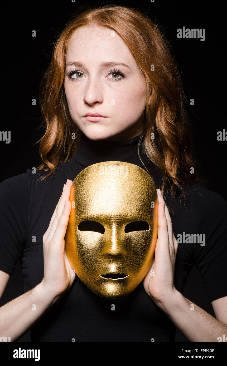 Redhead woman iwith mask in hypocrisy consept against black background ...