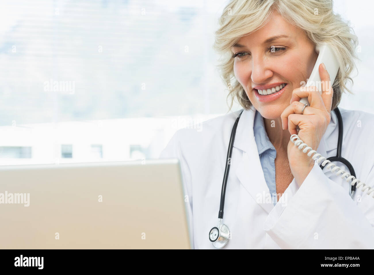 Female doctor using laptop and phone in medical office Stock Photo - Alamy