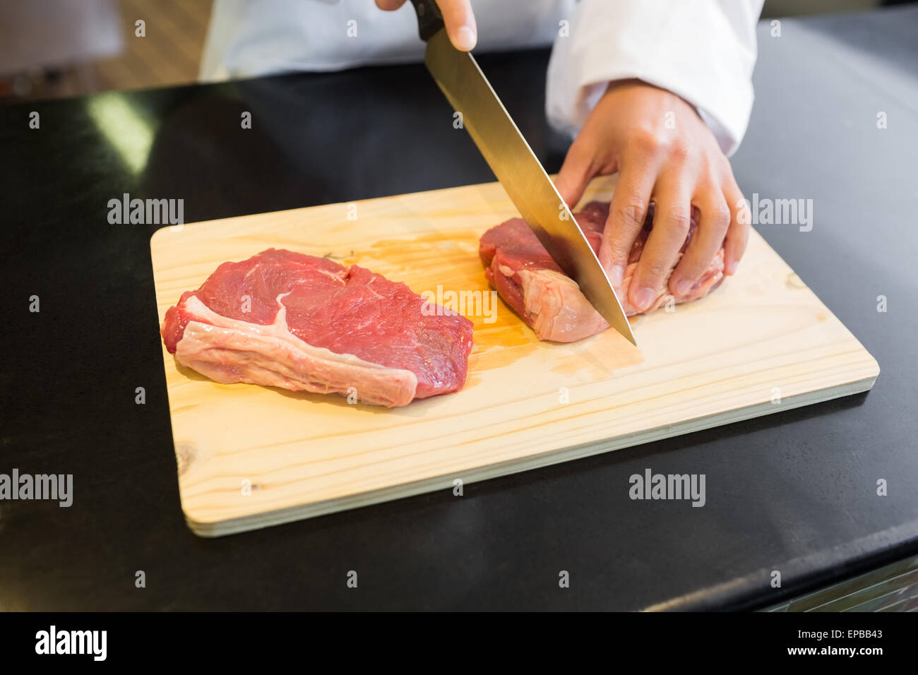 Mid section of hands cutting meat Stock Photo - Alamy