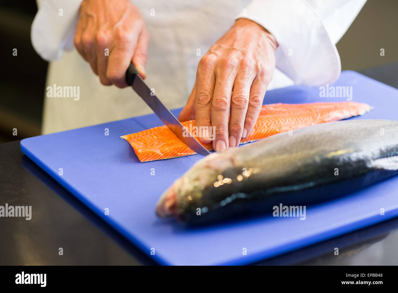 Closeup mid section of a chef cutting fish Stock Photo - Alamy
