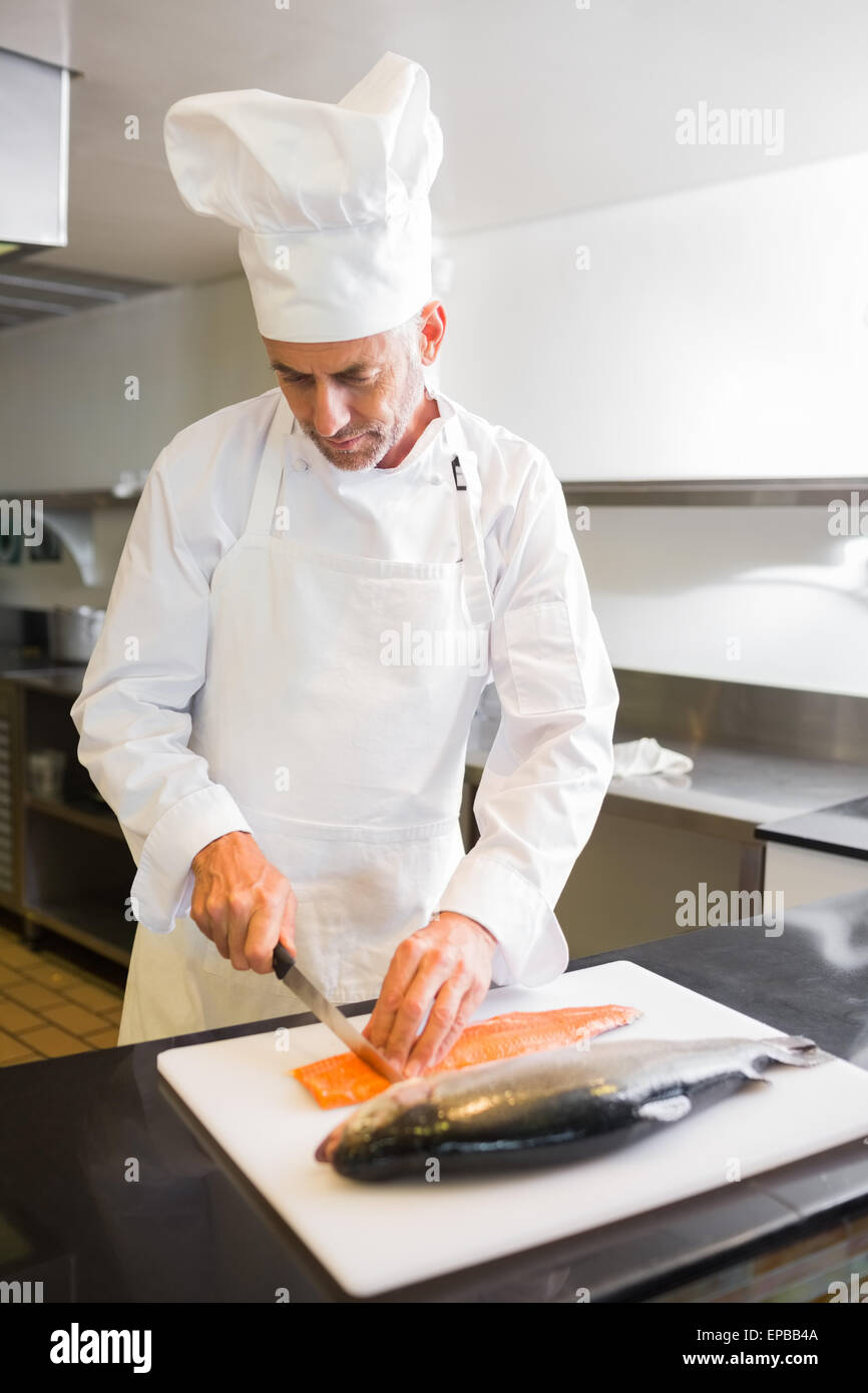 Concentrated male chef cutting fish in kitchen Stock Photo - Alamy