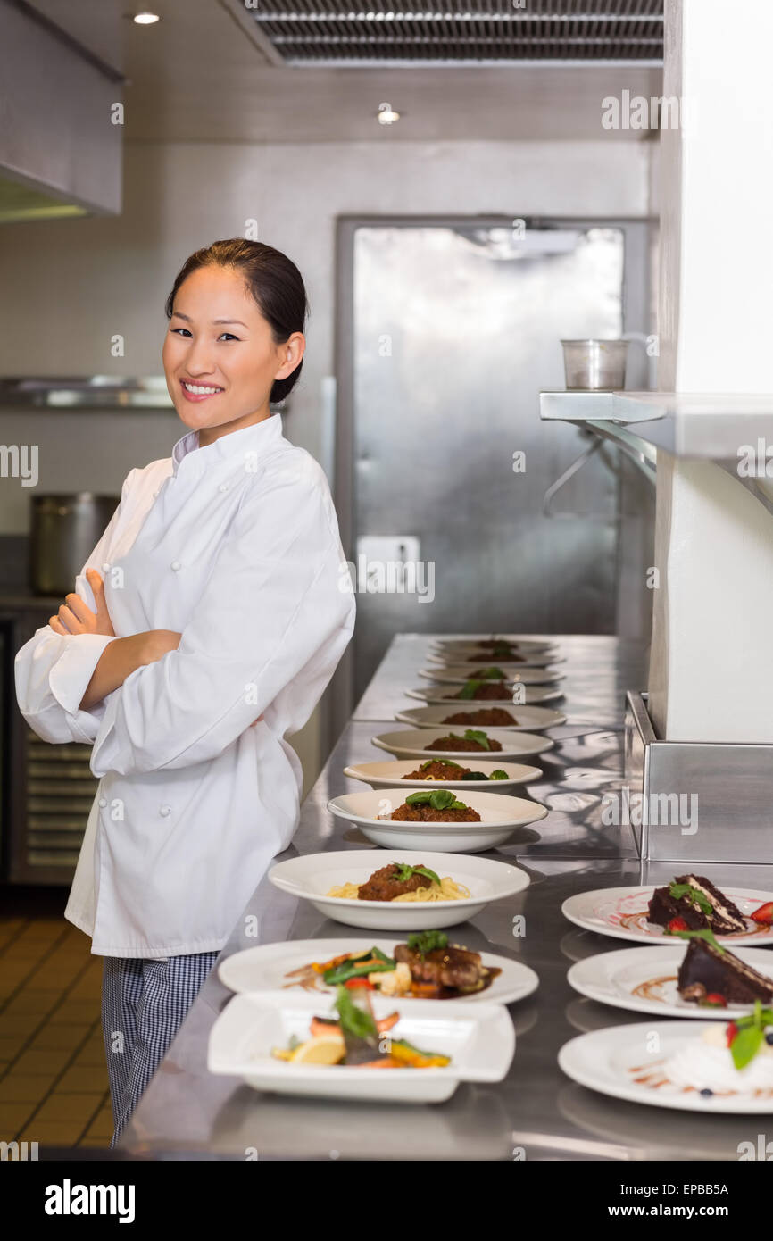 Confident female chef besides cooked food in row at kitchen Stock Photo ...