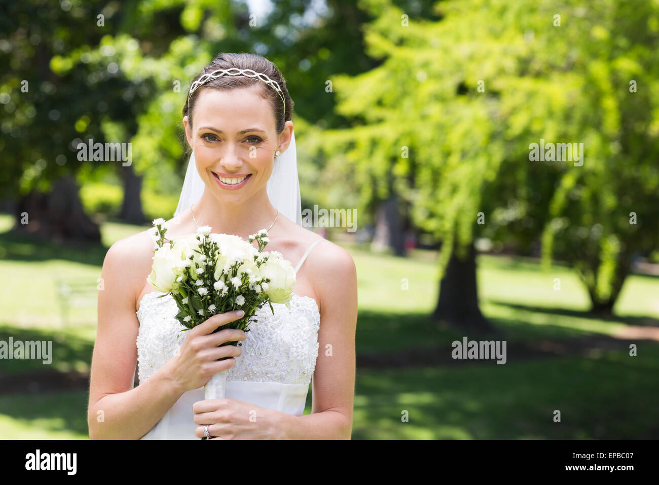 Attractive bride holding flower bouquet in garden Stock Photo - Alamy