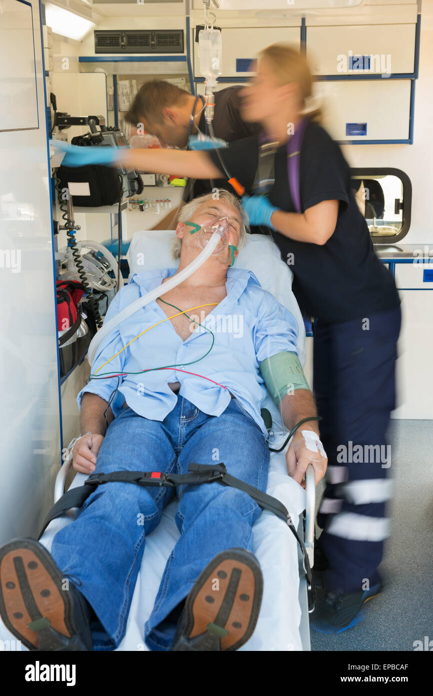 Paramedical team treating patient on stretcher Stock Photo - Alamy