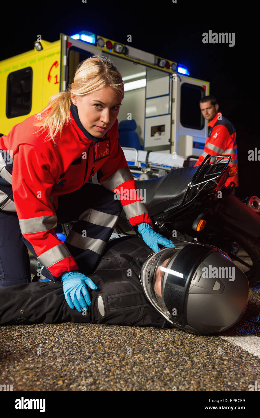 Paramedic assisting motorbike driver at night Stock Photo - Alamy