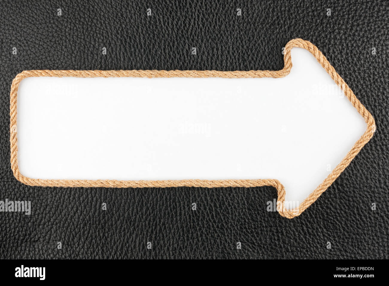 Arrow made of rope lies on a background of black leather, with place ...