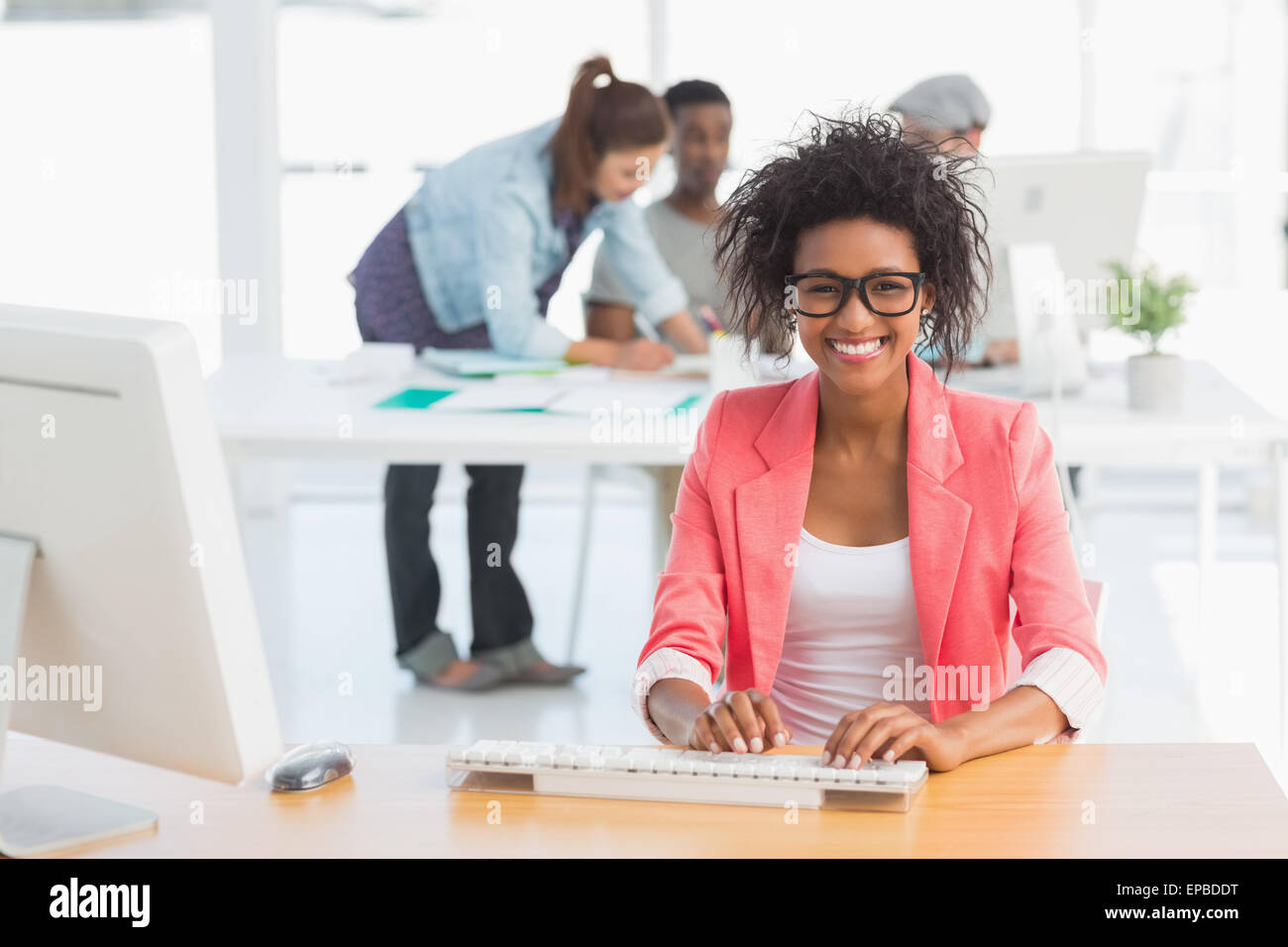 Female artist using computer with colleagues in background at office ...