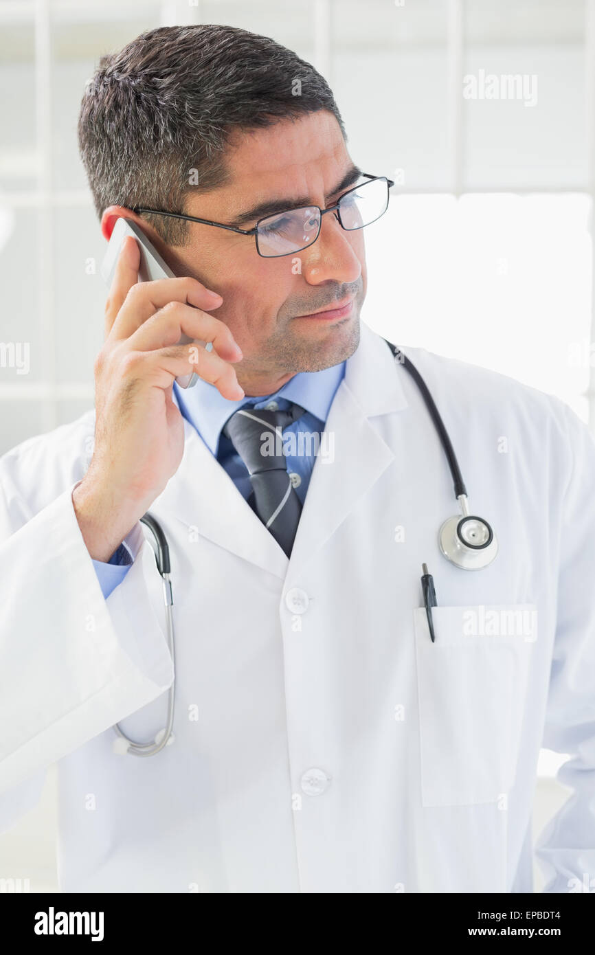 Serious male doctor using mobile phone Stock Photo - Alamy