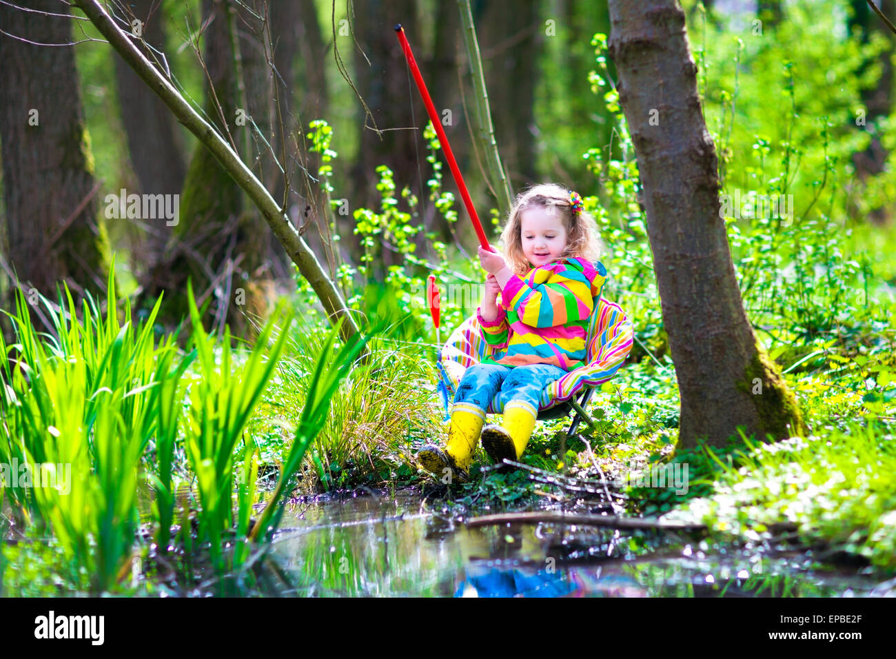 Child playing outdoors. Preschooler kid catching fish with red rod ...