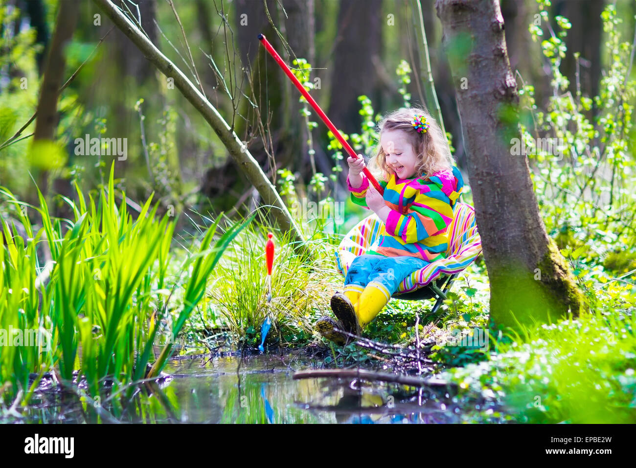 Child playing outdoors. Preschooler kid catching fish with red rod ...