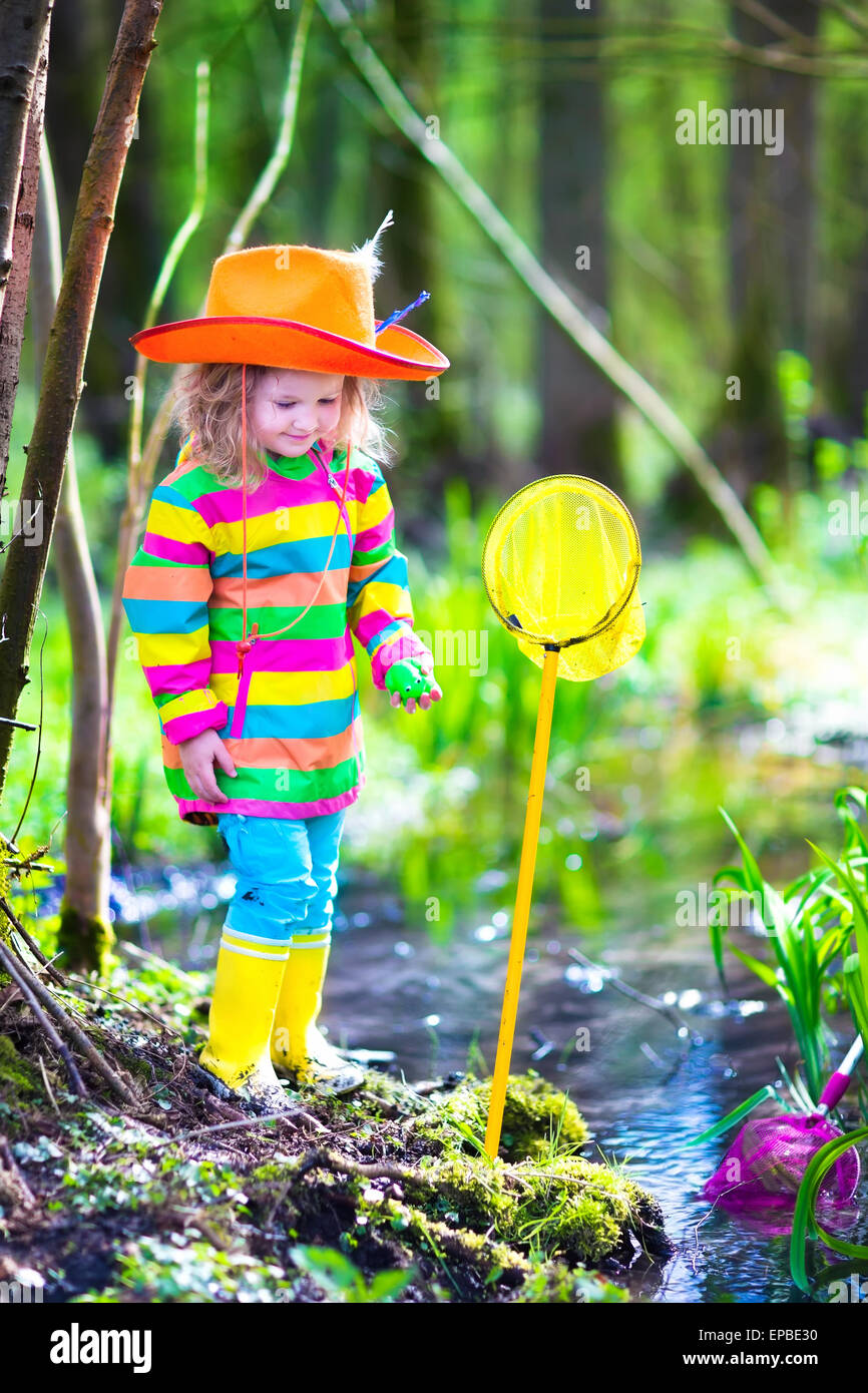 Child playing outdoors. Preschooler kid catching frog with colorful net ...