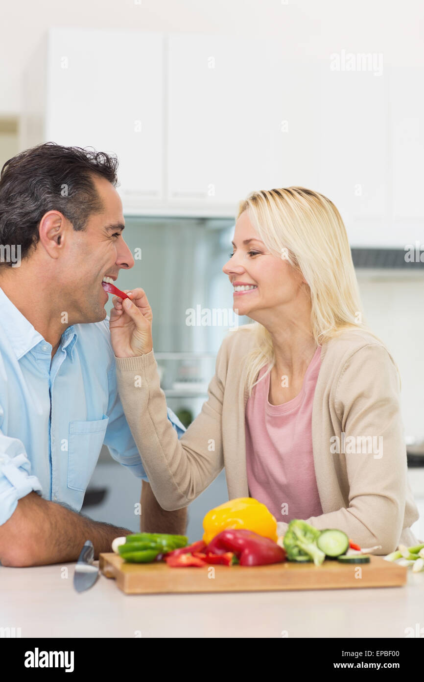 Happy loving woman feeding man vegetable in kitchen Stock Photo - Alamy