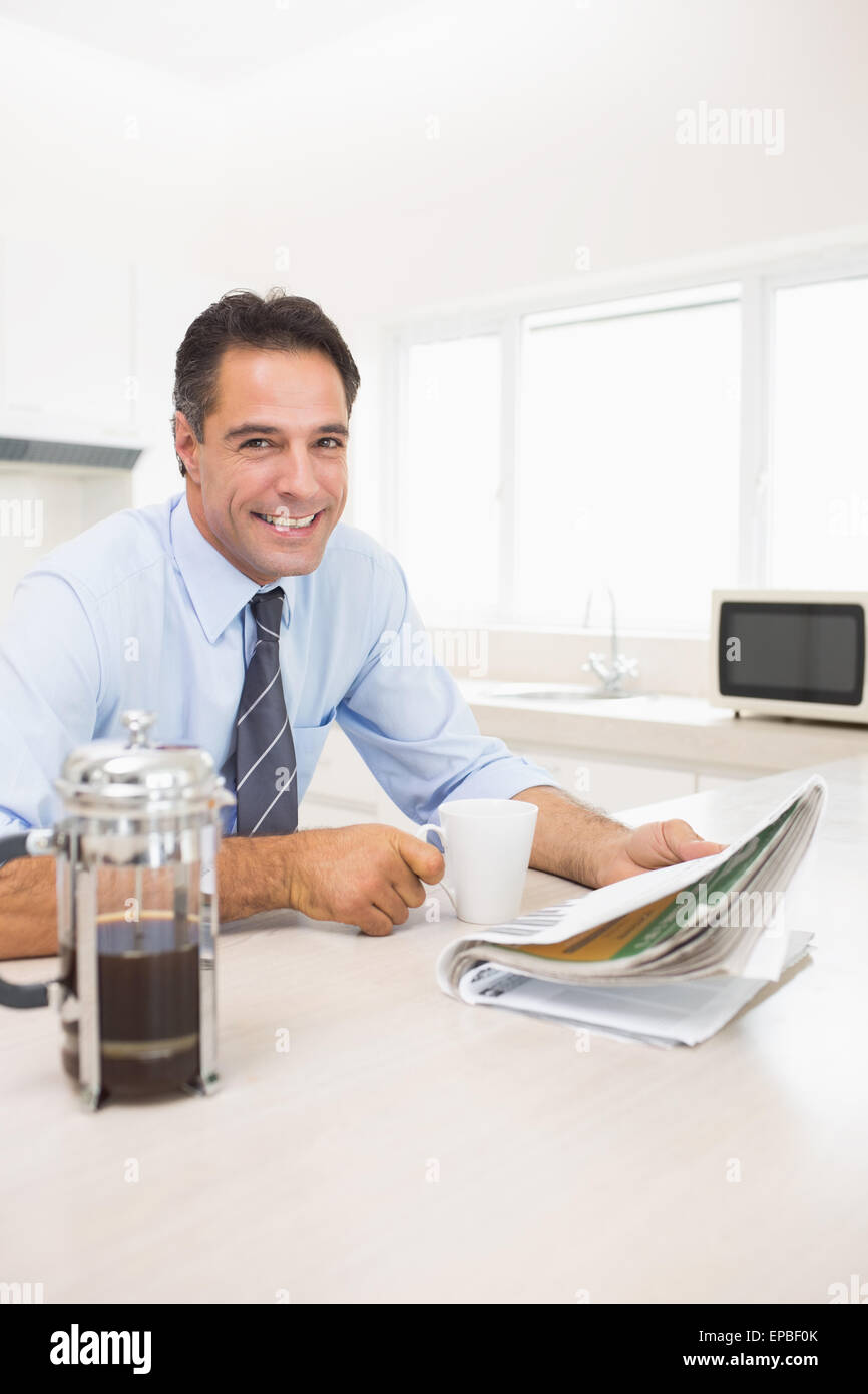 Smiling well dressed man with coffee cup and newspaper in kitchen Stock ...