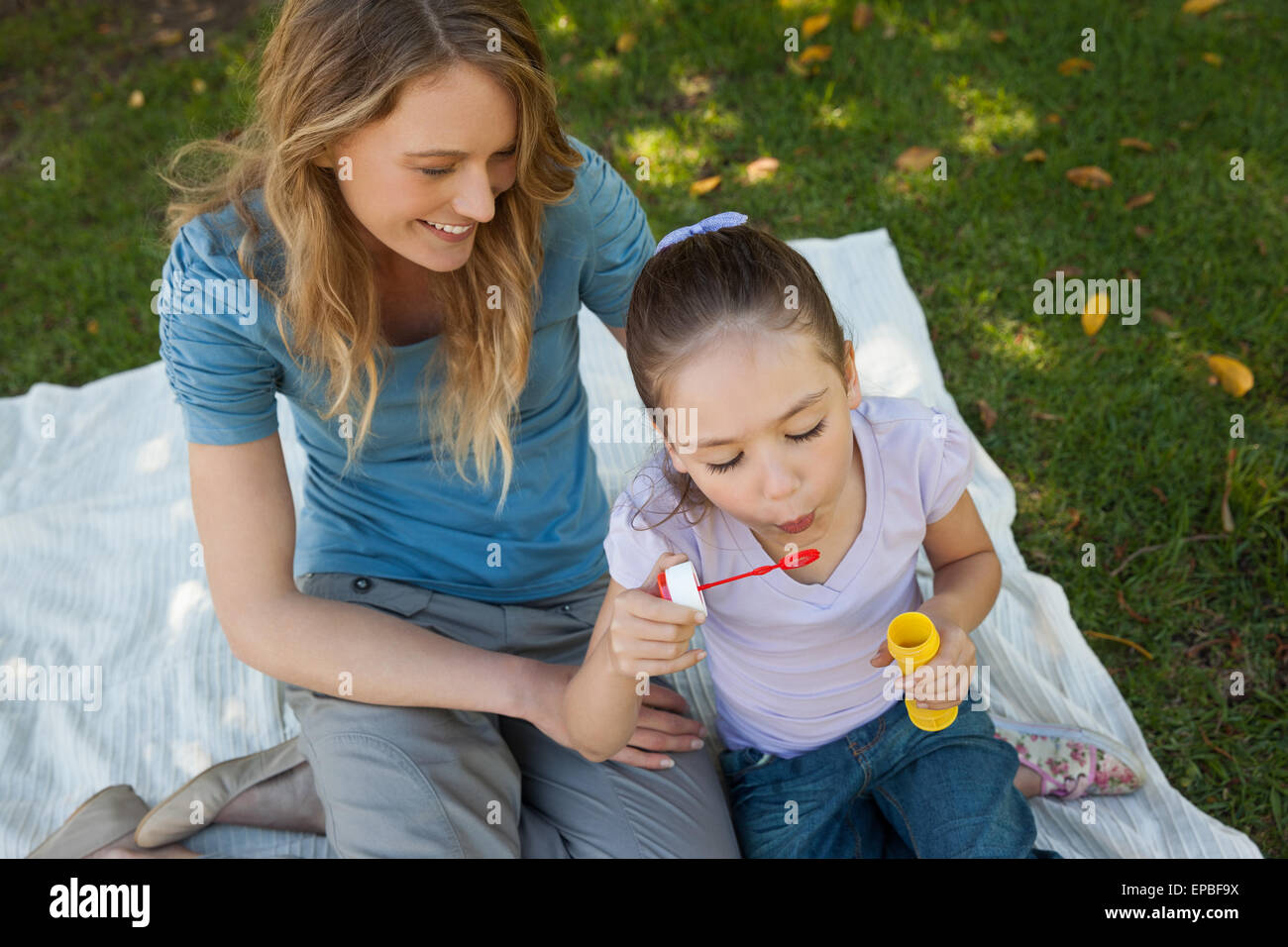 Mother with her daughter blowing soap bubbles at park Stock Photo - Alamy