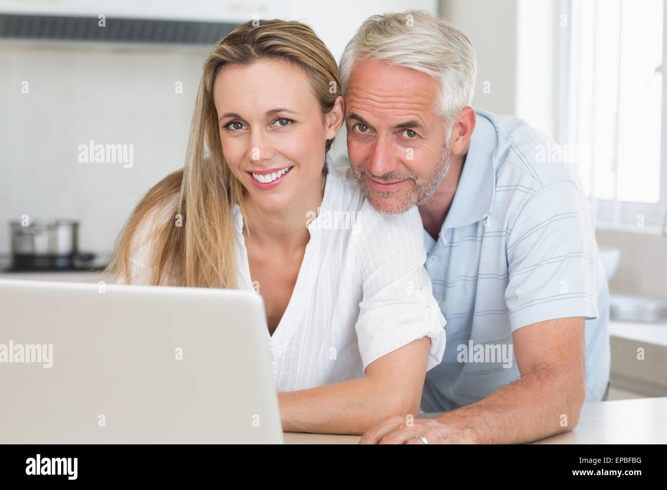 Happy couple using laptop together at the counter Stock Photo - Alamy