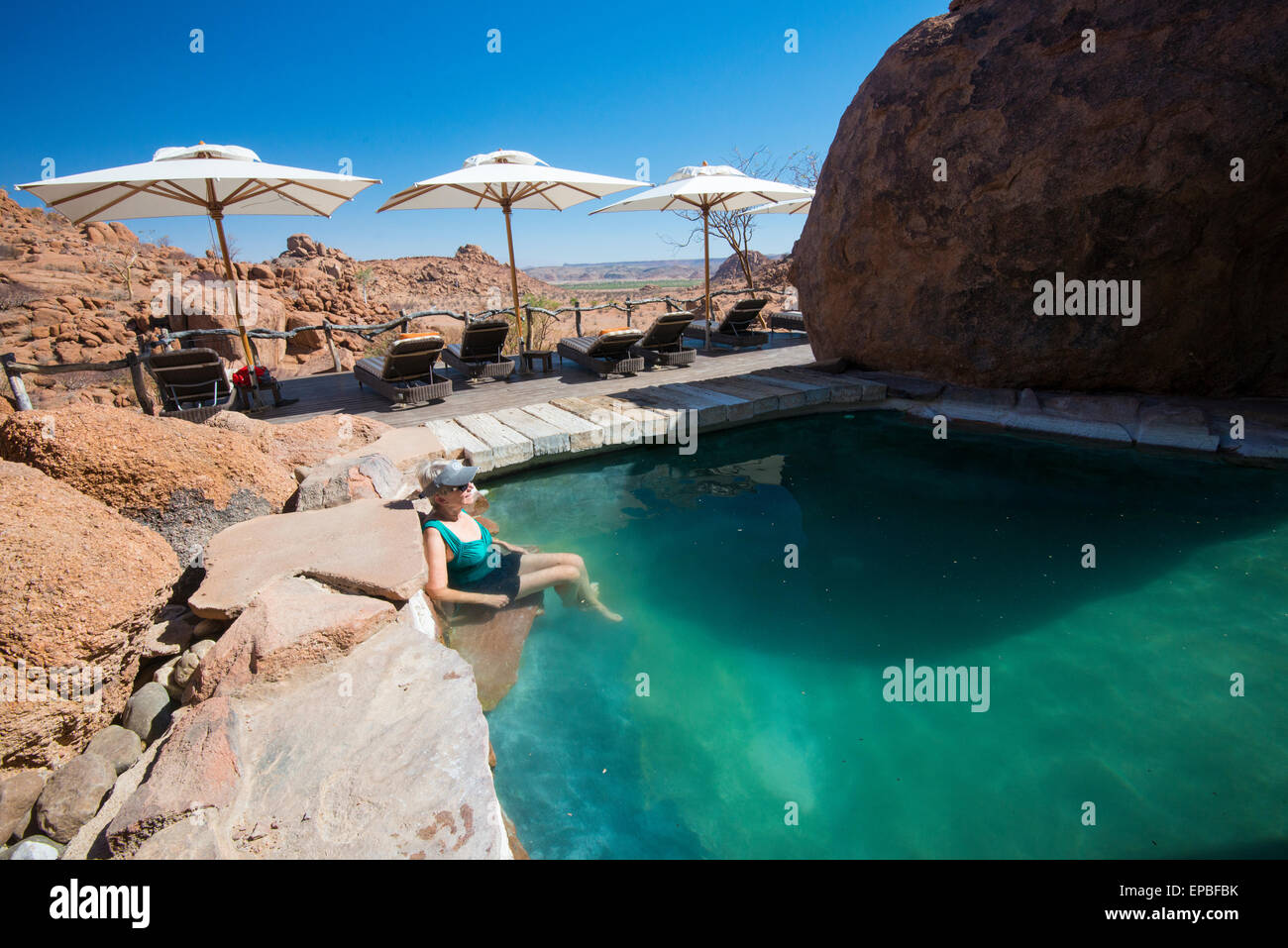 Africa, Namibia. Mowani Mountain Camp. Pool with woman relaxing on ...