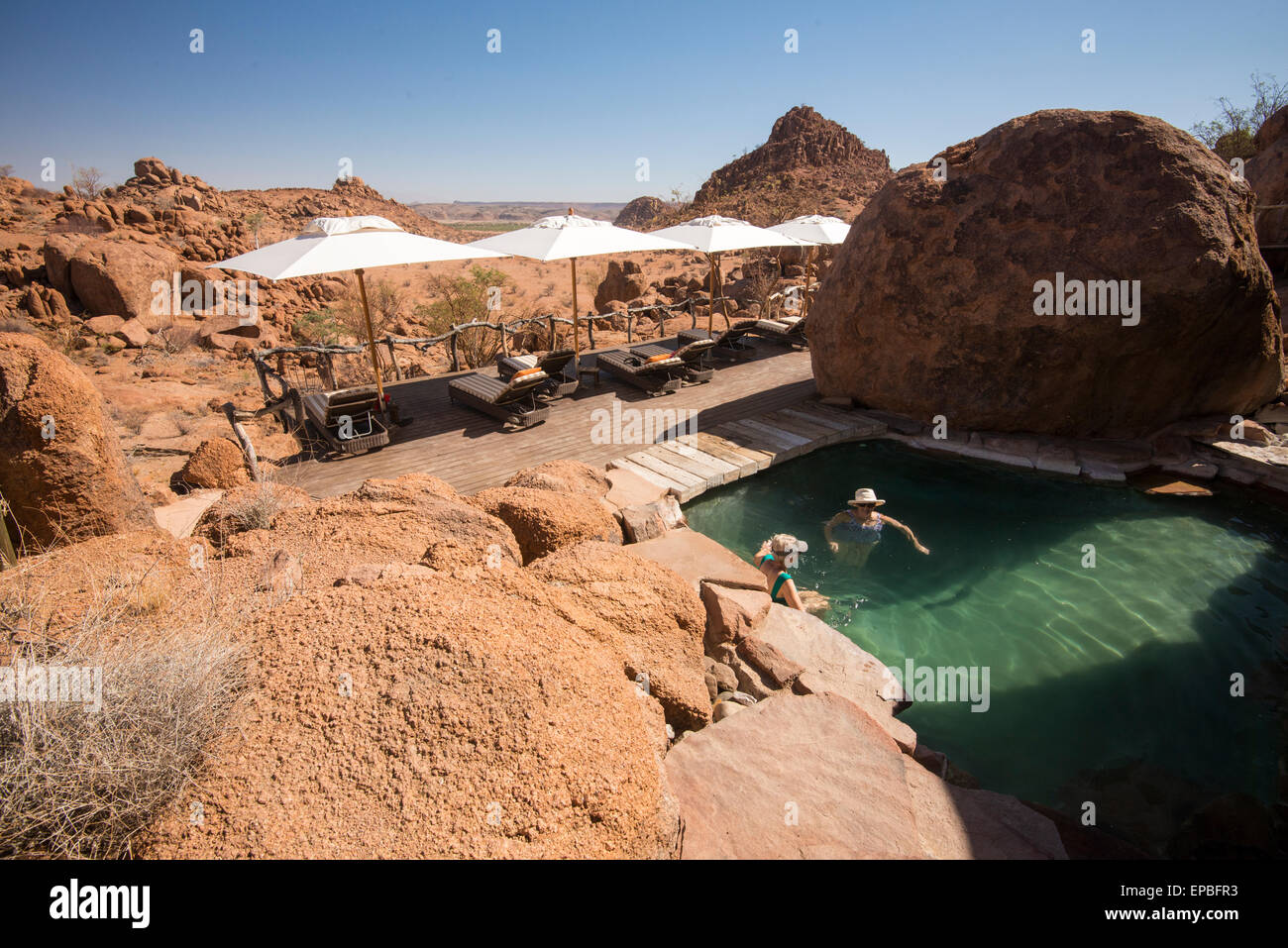 Africa, Namibia. Mowani Mountain Camp. Two woman swimming in relaxing ...