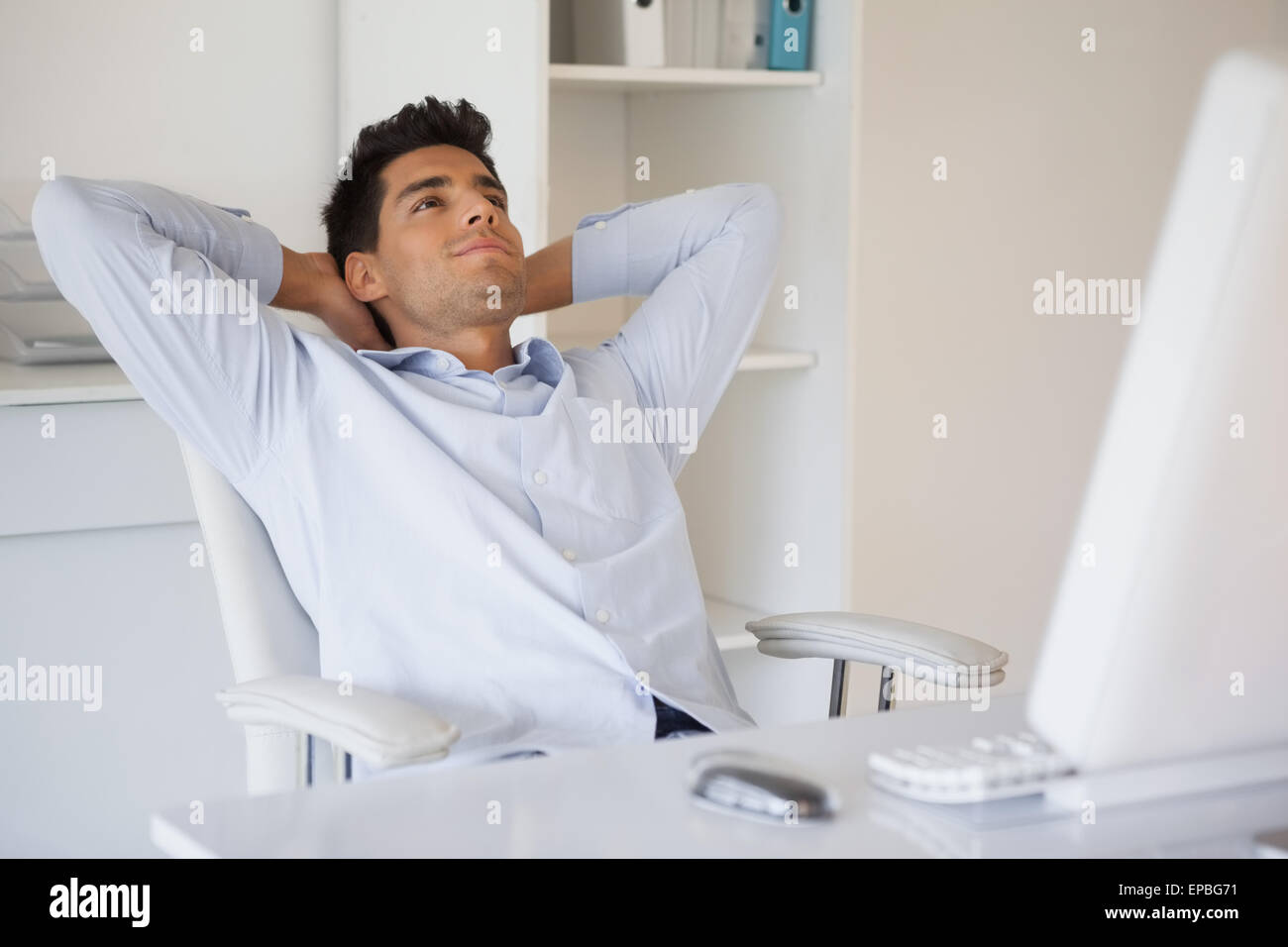 Casual businessman relaxing at desk leaning back Stock Photo - Alamy