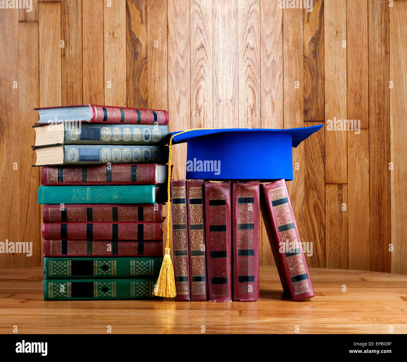 Graduation mortarboard on top of stack of books on wooden background of ...