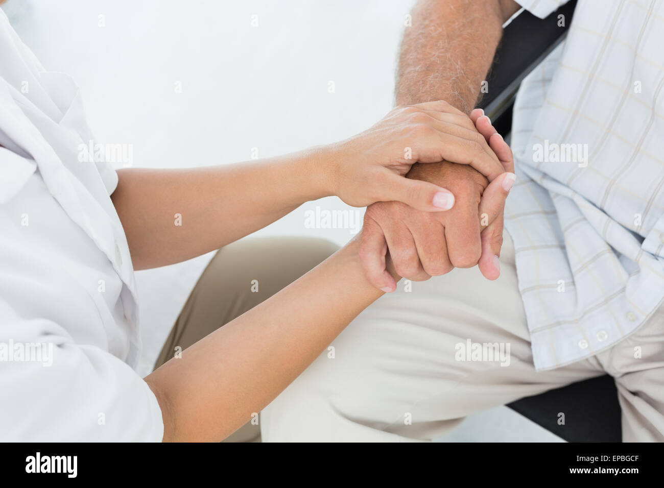 Mid section of a doctor holding patients hand Stock Photo - Alamy