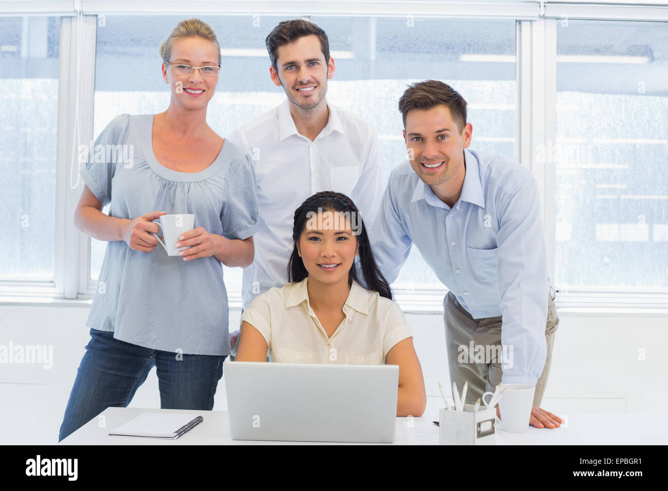 Casual business team using laptop together at desk Stock Photo - Alamy