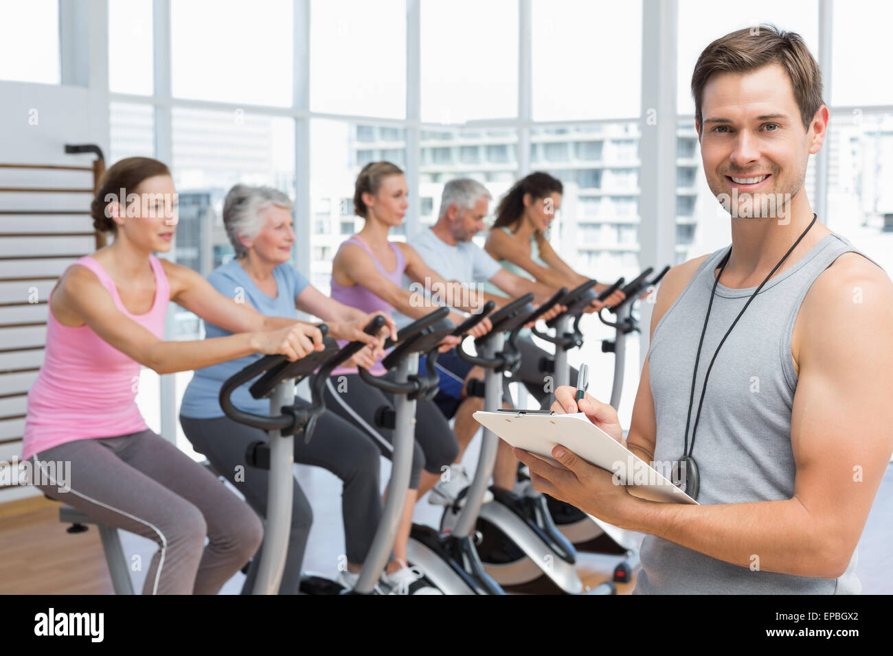 Portrait of a trainer with people working out at spinning class in gym ...