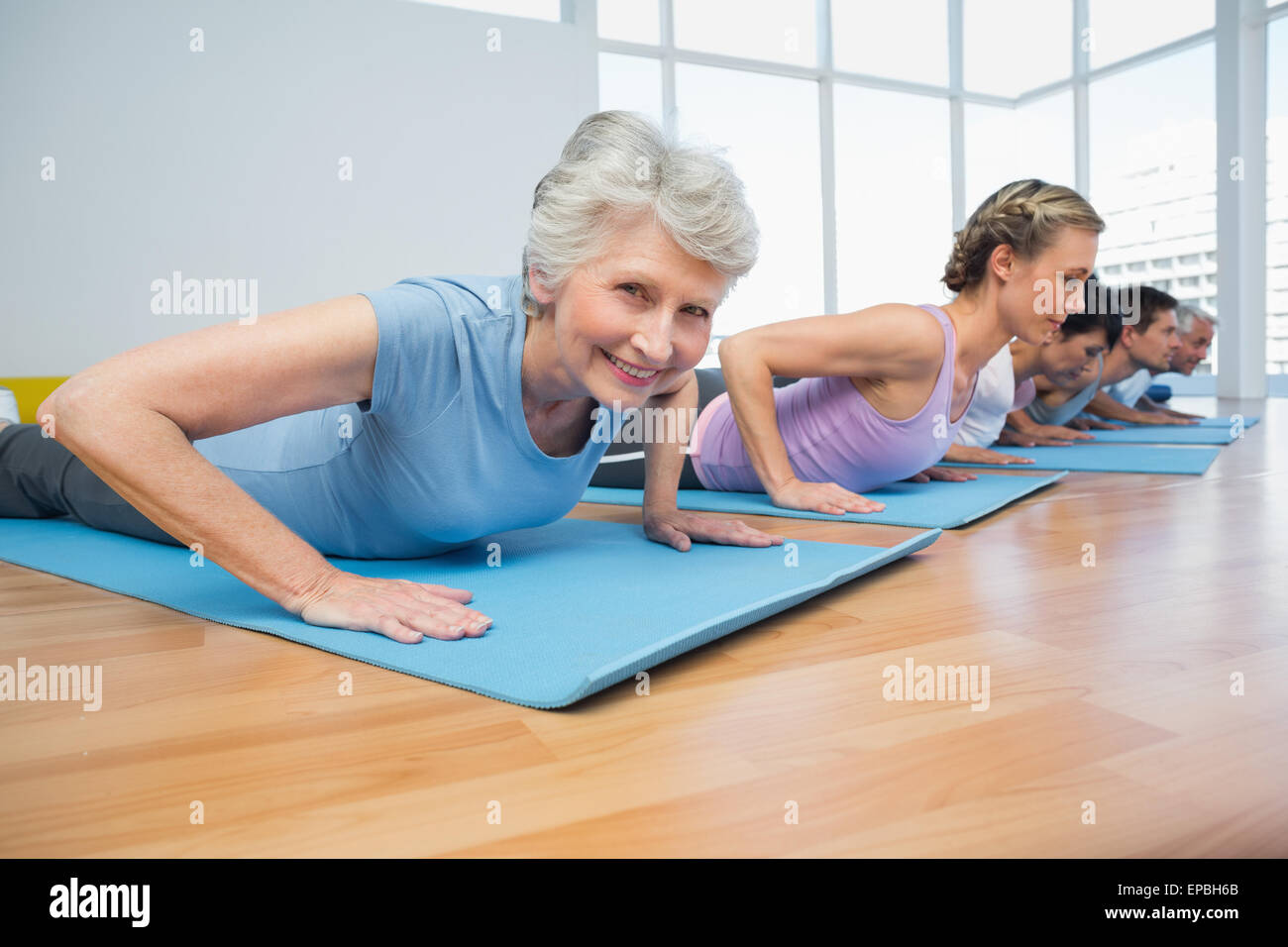 Group doing cobra pose in row at yoga class Stock Photo - Alamy