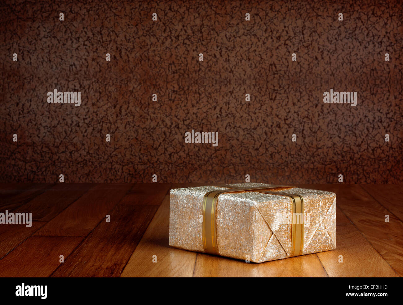 Gift box in gold wrapping paper with ribbon on wooden table Stock Photo ...