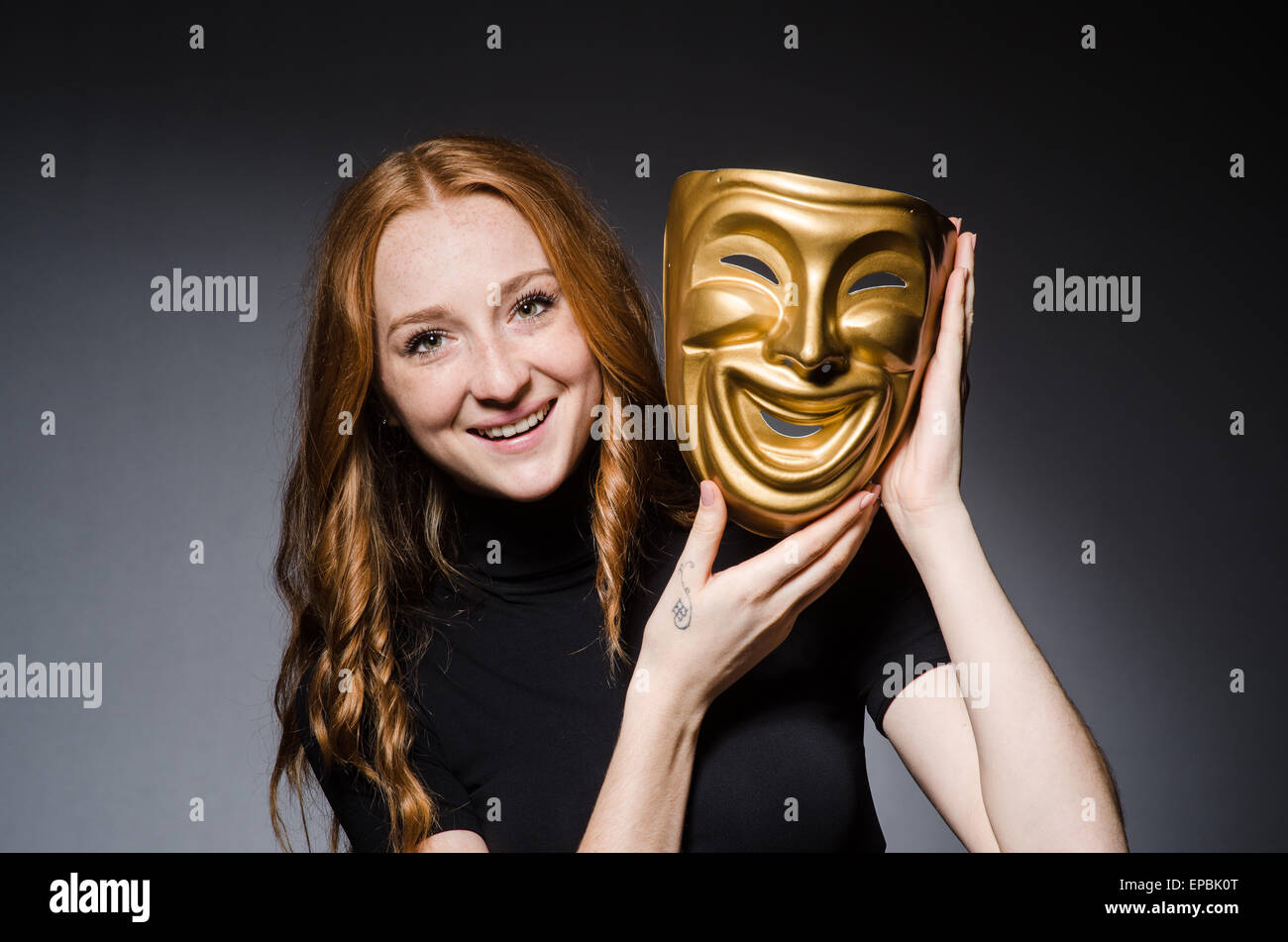 Redhead woman iwith mask in hypocrisy consept against grey background ...