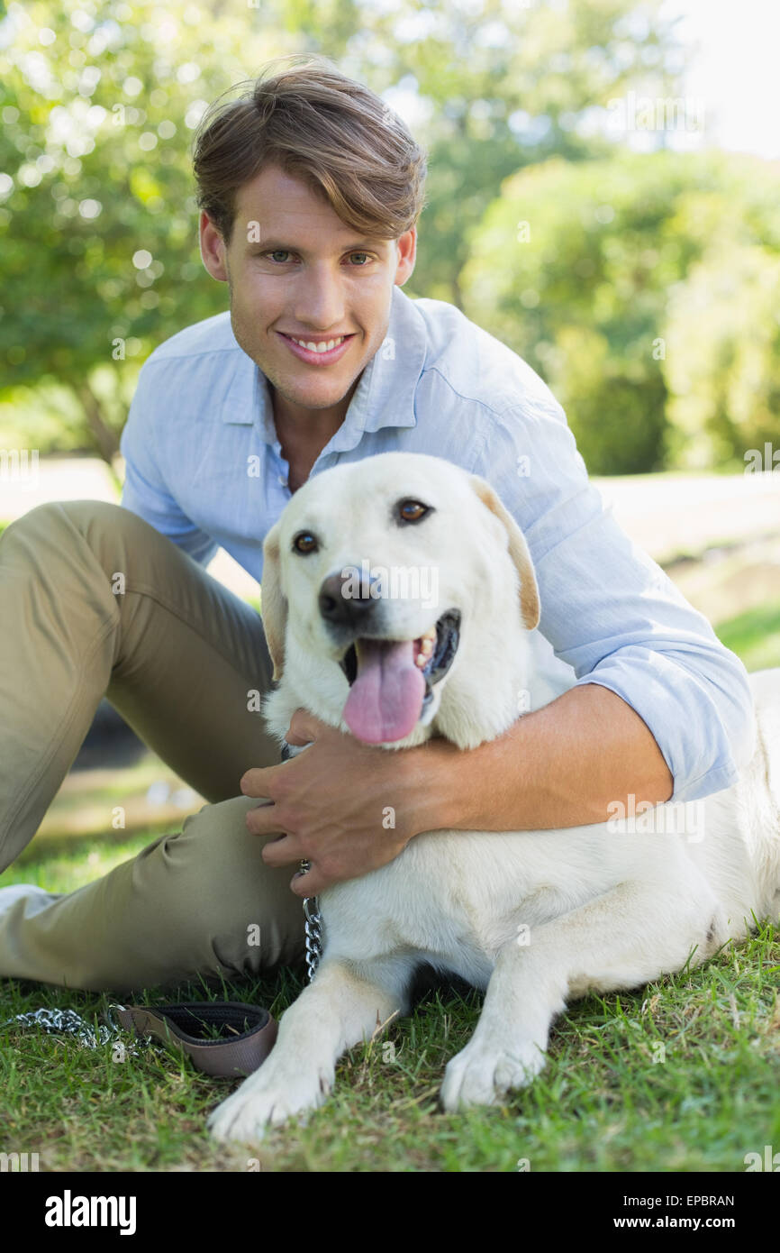 Handsome smiling man with his labrador sitting in the park Stock Photo ...