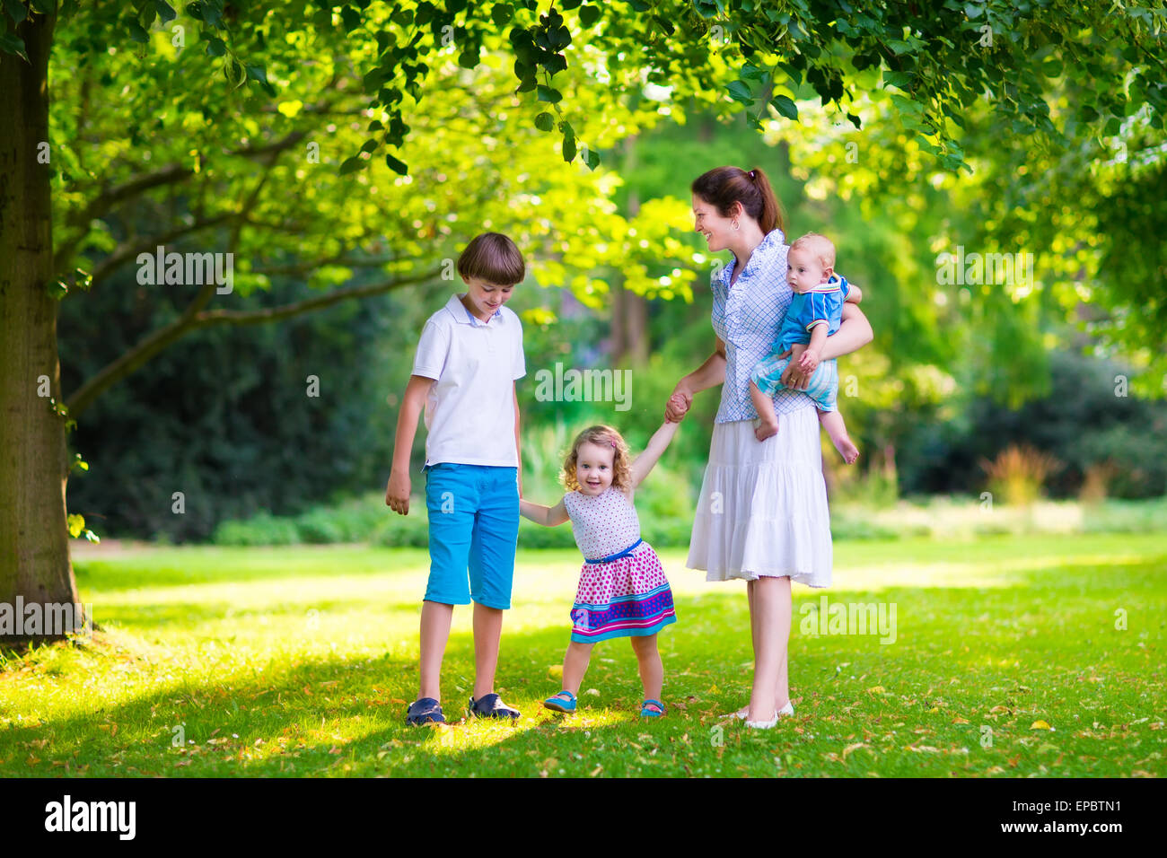 Happy family with three kids in a park. Young mother with children ...