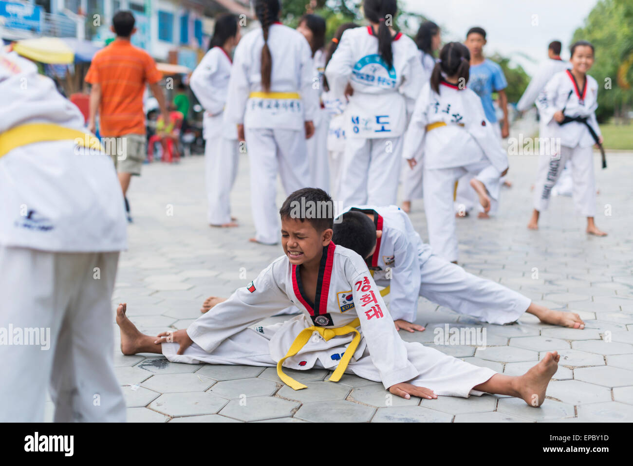 Young boy with strained expression on his face, stretching hard in Tae ...
