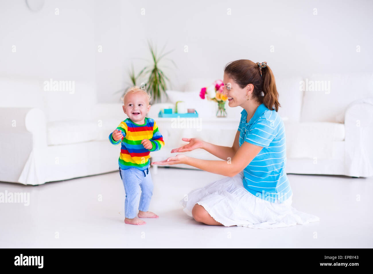 Cute little baby boy making his first steps, walking to his mother in a ...