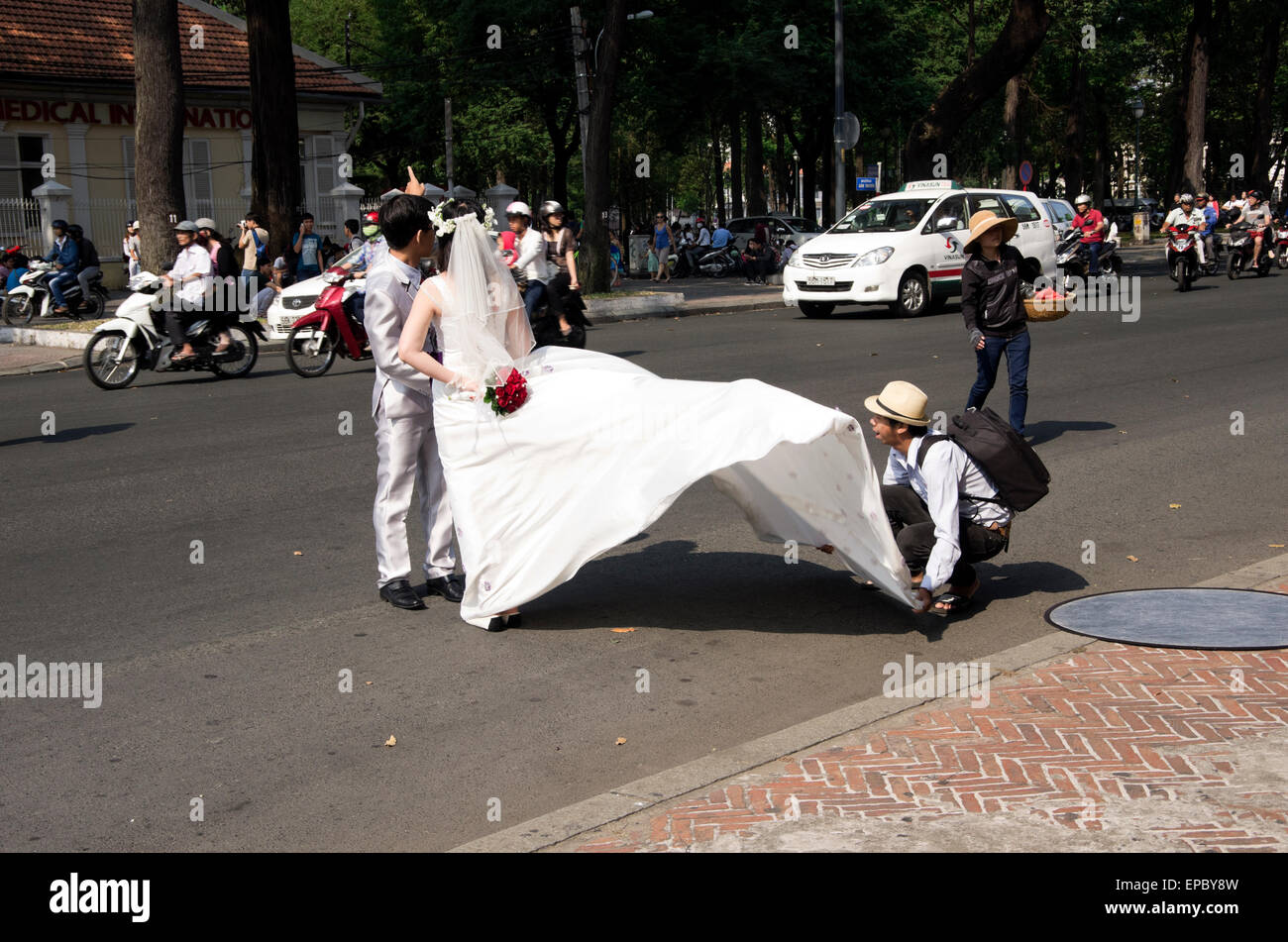 Bride and groom being photographed in street at side of cathedral as ...