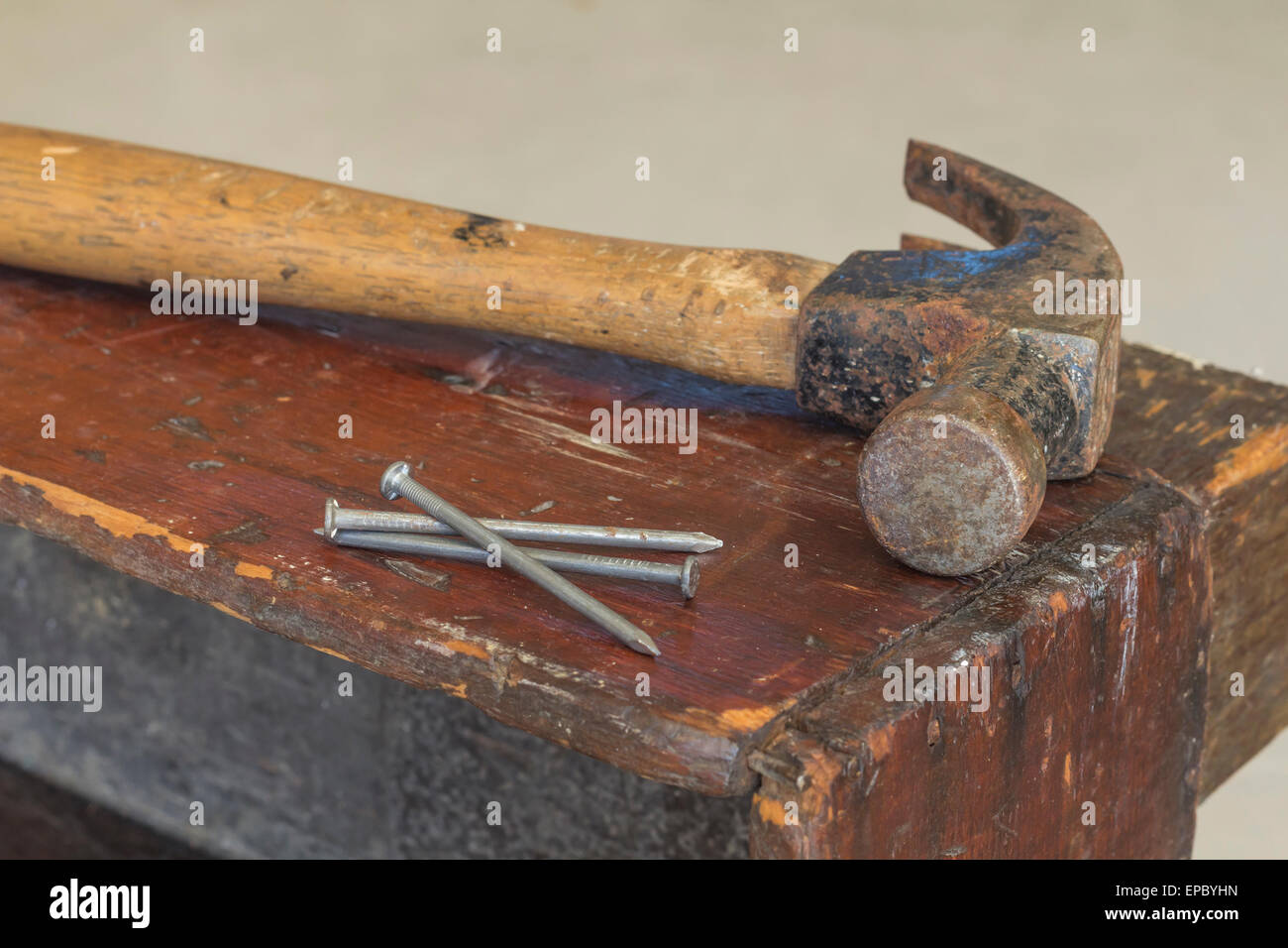 Old and worn contracting hammer and three nails on a distressed work ...