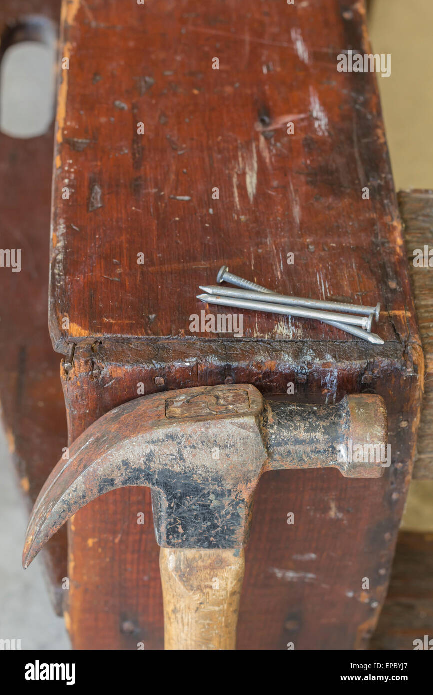 Old and worn contracting hammer and three nails on a distressed work ...