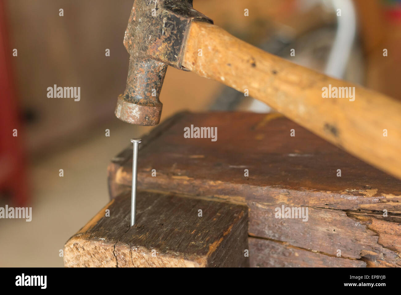 Old and worn contracting hammer and three nails on a distressed work ...