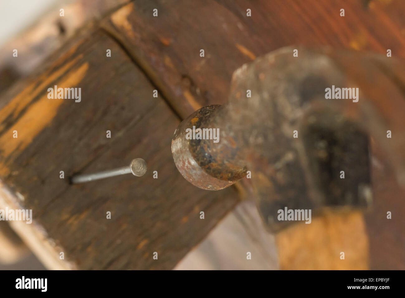 Old and worn contracting hammer and three nails on a distressed work ...