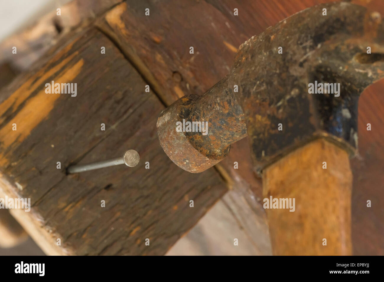 Old and worn contracting hammer and three nails on a distressed work ...